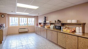 Uma cozinha ampla com piso ladrilhado, janela com vista e micro-ondas na bancada.