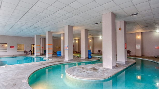 Piscina interior com várias pistas, sustentada por colunas e ladeada por paredes com avisos.
