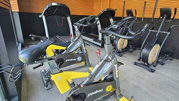 Uma academia com bicicletas ergométricas, esteiras e equipamentos de exercícios.