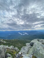 Paisagem montanhosa com terreno rochoso e um lago ao longe.