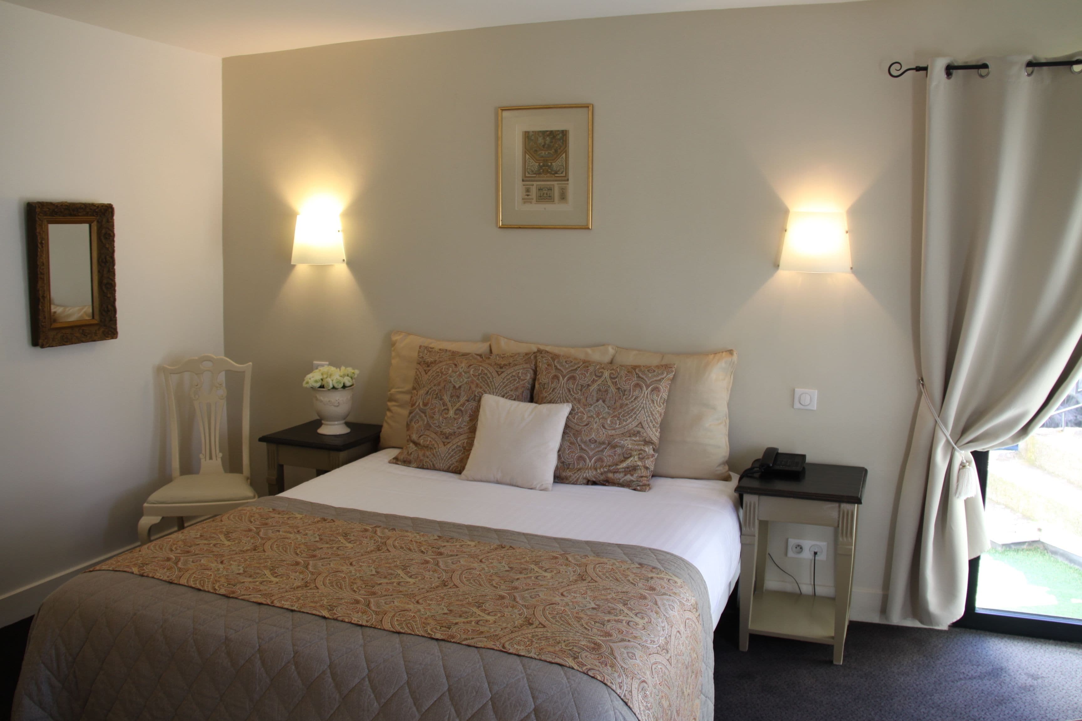 Quarto bem arrumado com uma cama grande, duas luminárias de cabeceira, mesa de cabeceira, uma cadeira e uma janela com cortinas.