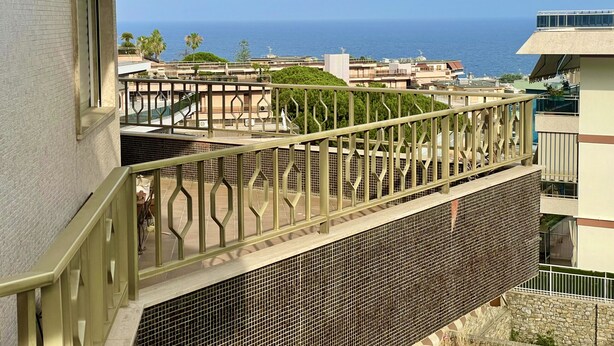 Uma varanda com vista para o mar e edifícios vizinhos.