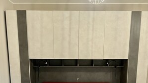 Quarto moderno com cama grande, cabeceira com armários embutidos e luminária pendente.