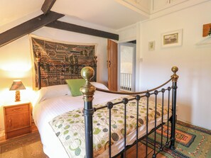 Quarto com cama, mesa de cabeceira, tapeçaria na parede e janela com cortinas.