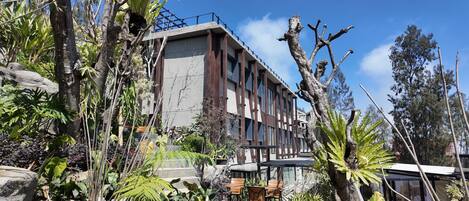 Um edifício moderno com varanda e área de jardim com diversas plantas e espaço para sentar.