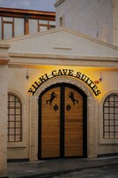 Um edifício com uma placa que diz "YILK CAVE SUITES" acima de uma porta de madeira com silhuetas de cavalos.