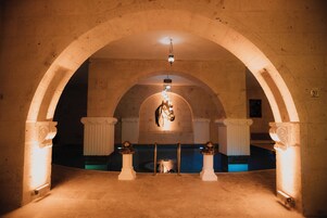 Um interior em arco com um candelabro central, colunas e piso de azulejos.