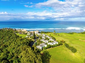 Zona residencial costeira com casas, campo de golfe e vista para o oceano.