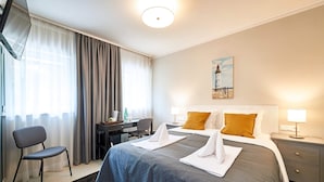 Quarto de hotel com cama, duas mesas de cabeceira, uma escrivaninha, uma cadeira e um quadro na parede.