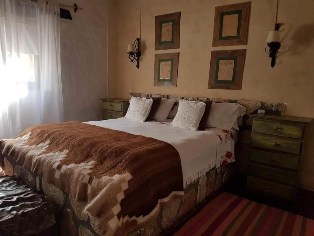 Quarto com uma cama grande, cabeceira de madeira, mesa de cabeceira e cômoda.