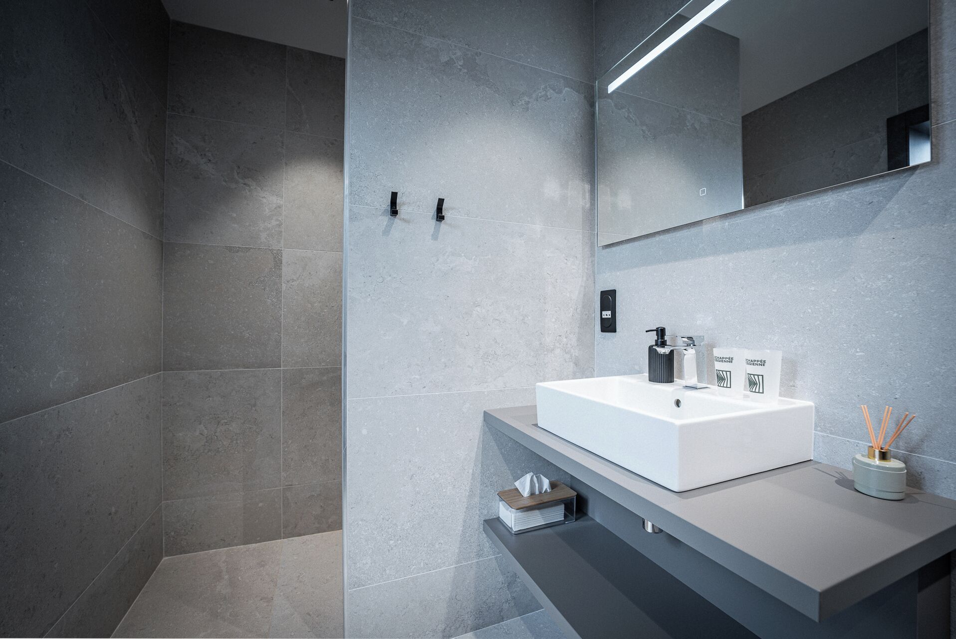 Uma casa de banho moderna com lavatório branco, espelho e zona de duche.