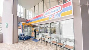 Uma loja Indomaret Point com fachada de vidro, área de estar externa e placa de saída visível.