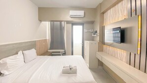 Quarto de hotel com cama, televisão fixada na parede e aparelho de ar condicionado.