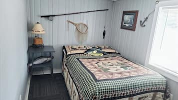 Quarto com cama, escrivaninha, luminária e janela.