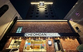 Exterior do Hotel Cheomdan, com fachada de tijolos e sinalização iluminada.