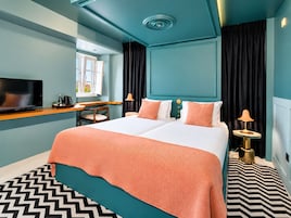 Quarto de hotel moderno com uma cama grande, uma escrivaninha, uma televisão e vista para o exterior.