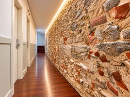 Um corredor com piso de madeira e parede texturizada com tijolos e pedras.