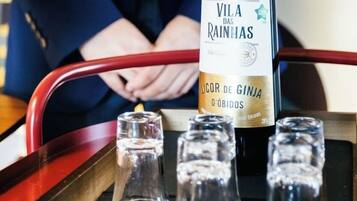 Uma garrafa de vinho Vila das RAINHAS com quatro copos para shots em um suporte.