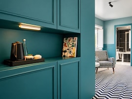 Quarto em tom de verde-água com design moderno, com uma cafeteira, uma garrafa e um objeto decorativo numa prateleira.