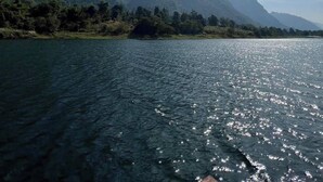 Um rio com montanhas ao fundo e o sol brilhando intensamente.