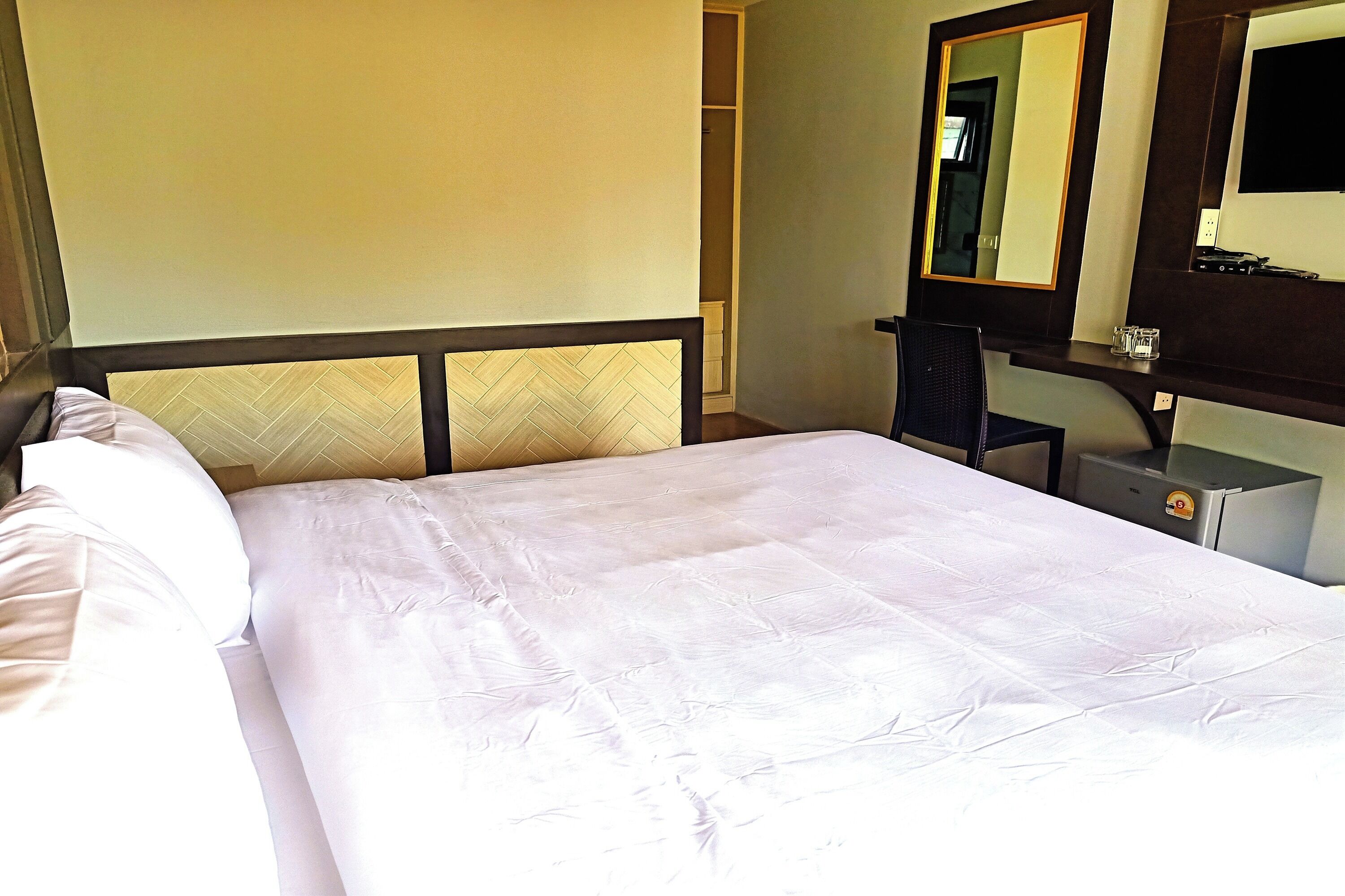 Quarto de hotel com uma cama grande, uma escrivaninha, um espelho e um guarda-roupa.