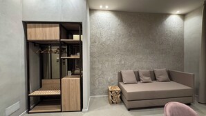 Quarto moderno com armário embutido, sofá e um pequeno banco de madeira.