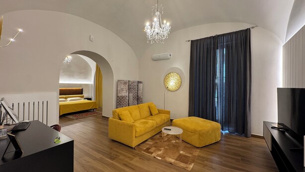 Uma sala de estar moderna com um sofá amarelo, uma mesa de centro redonda e um candelabro.
