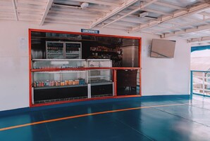 Uma área de bar com uma placa indicando 'Lanchonete' e um balcão refrigerado.