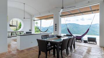 Uma área de refeições espaçosa com vista para as montanhas, uma rede e uma cozinha moderna.