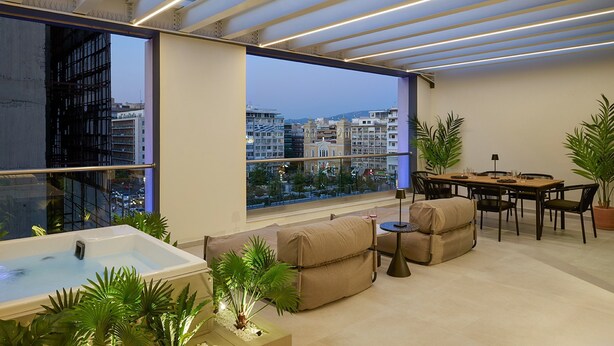 Uma sala de estar moderna com uma janela grande, um sofá, uma mesinha e um espaço para refeições.
