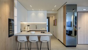 Cozinha moderna com ilha central, banquetas e frigorífico embutido.