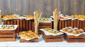 Um buffet com diversos pães e doces.
