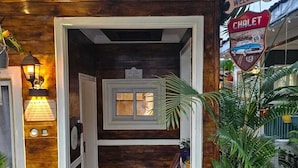 Um corredor com parede de madeira, placa de boas-vindas, sinalização para um chalé e plantas em vasos.