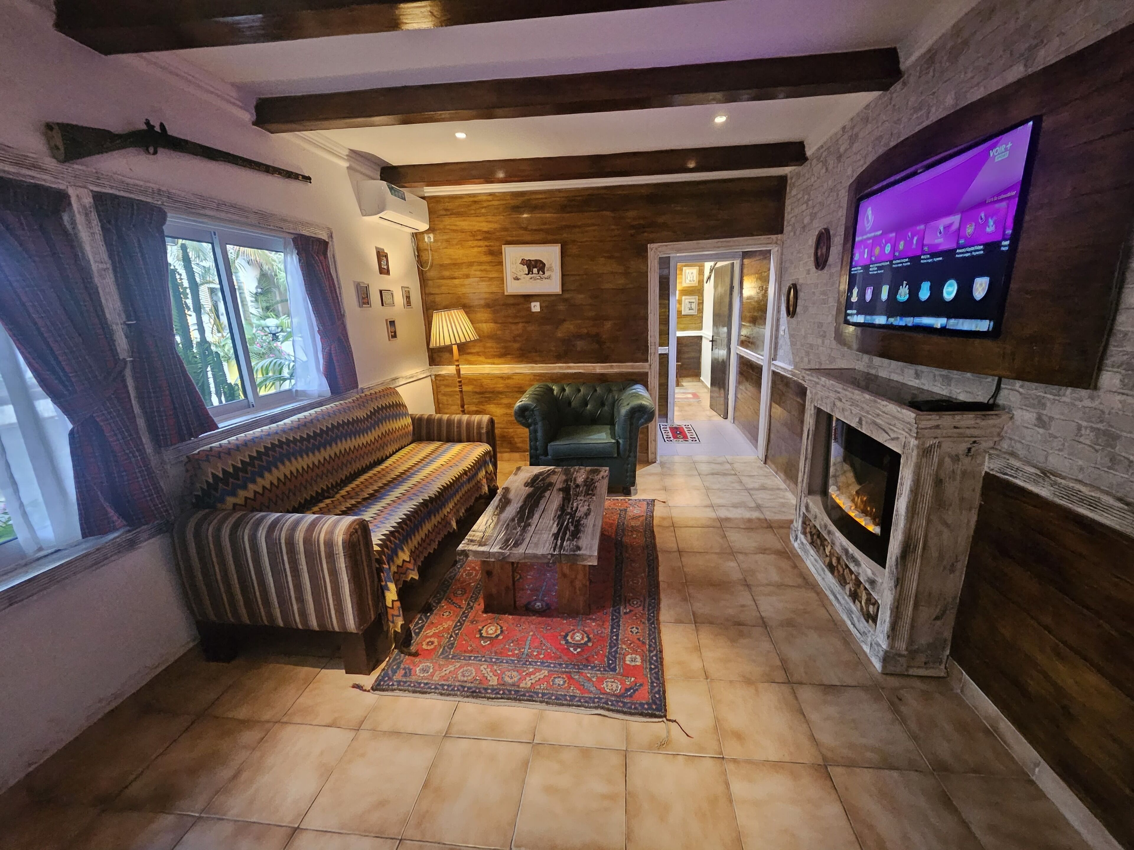 Sala de estar com sofá, lareira, televisão e vista para o exterior.