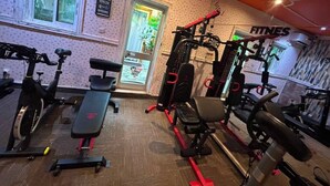Uma academia com bicicletas ergométricas, um banco e equipamentos de musculação.