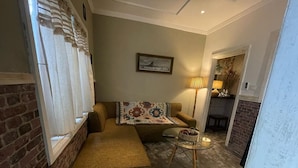 Uma sala de estar aconchegante com um sofá seccional, um cobertor estampado, uma mesinha de canto com velas e um quadro na parede.