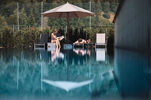 Uma piscina com espreguiçadeiras e um guarda-sol.