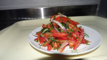 Uma salada fresca de tomate com cebola e ervas sobre um prato branco.