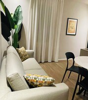 Uma sala de estar com sofá, mesa de centro e área de jantar com cadeiras.