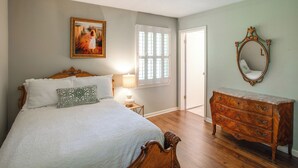 Quarto com cama, cômoda e uma pintura na parede.