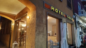 Um hotel chamado "HOTEL SOLE", com uma área de recepção visível e entrada por porta de vidro.
