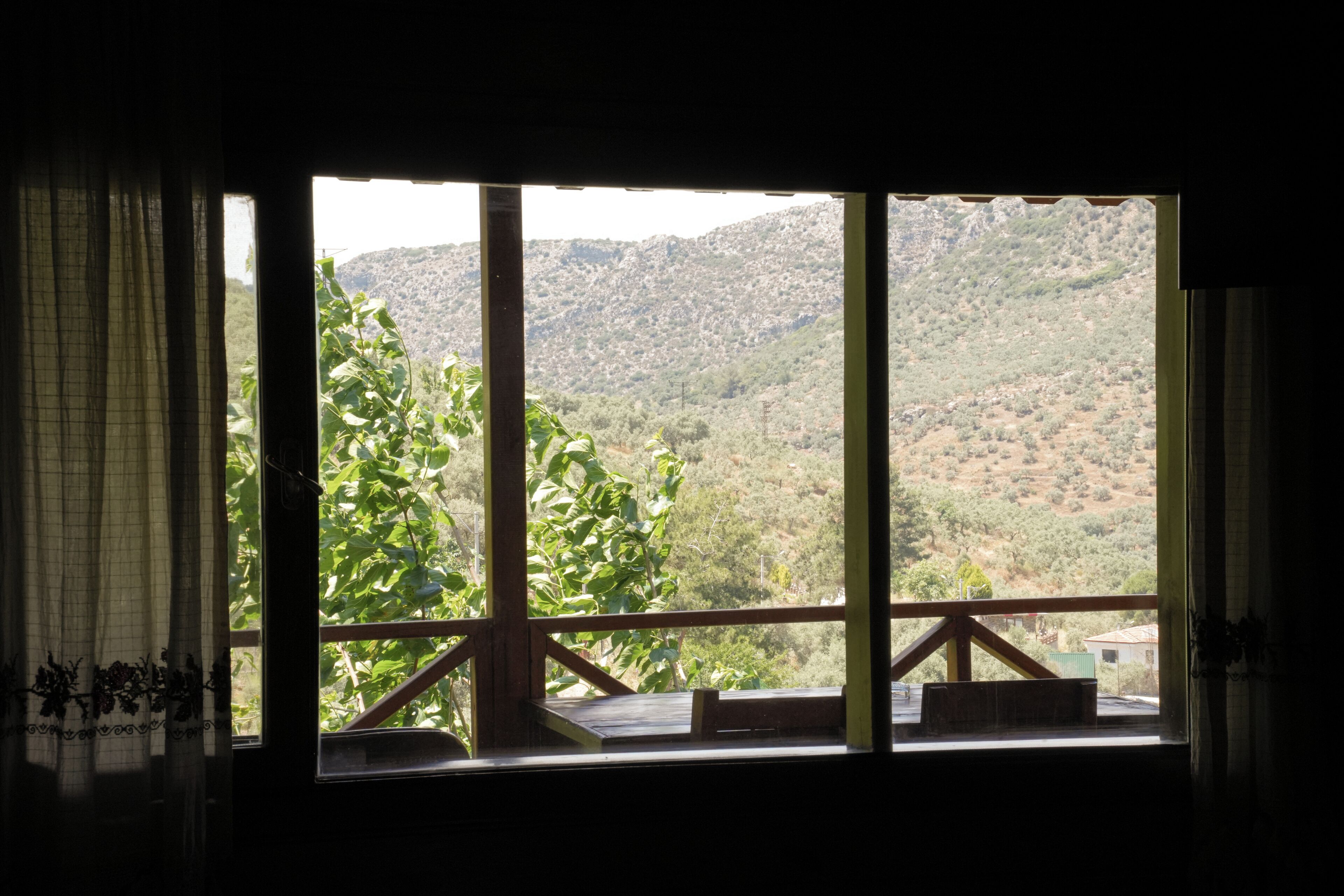Quarto com uma grande janela com vista para uma paisagem montanhosa.