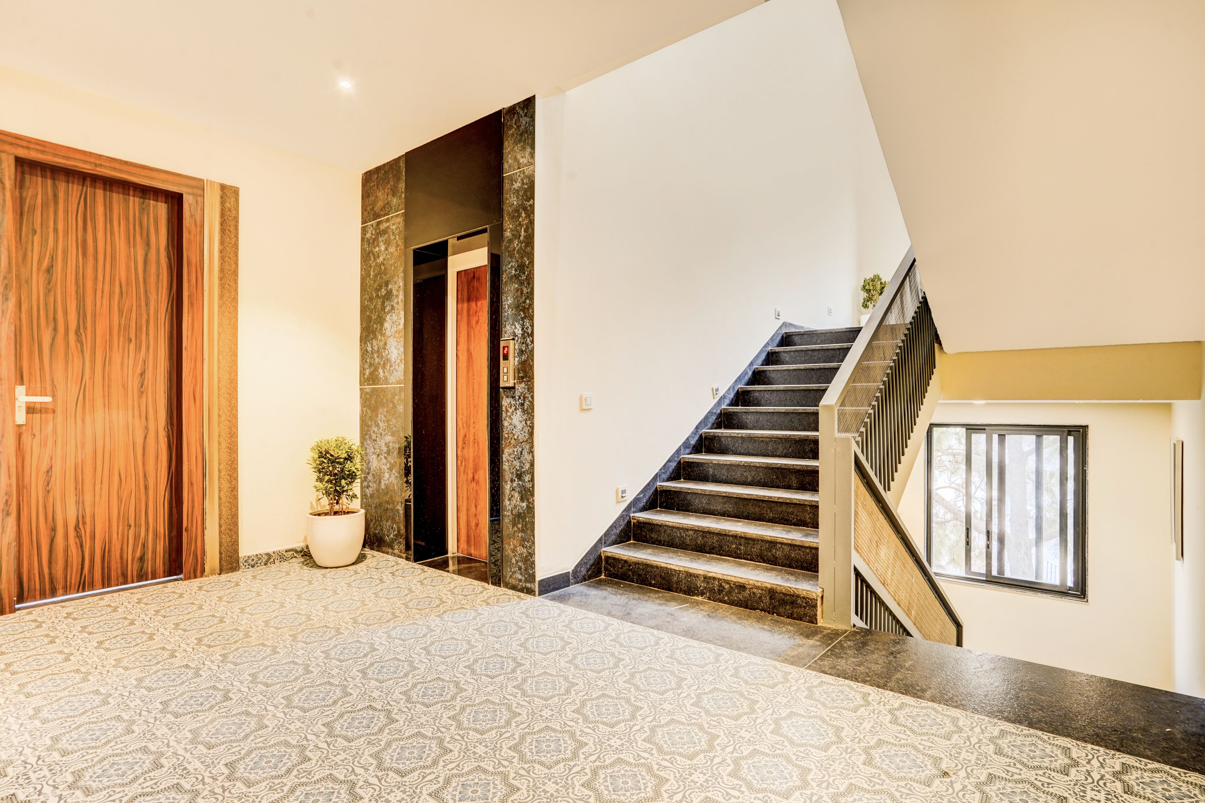 Um interior moderno com escada, porta de madeira e planta em vaso.