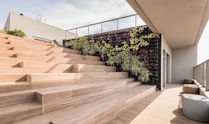 Uma escadaria moderna com um jardim vertical, degraus de madeira e assentos de vime.