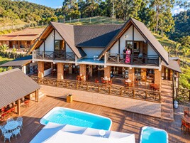 Um lodge de dois andares com piscina, área de estar externa e vista para as colinas ao redor.