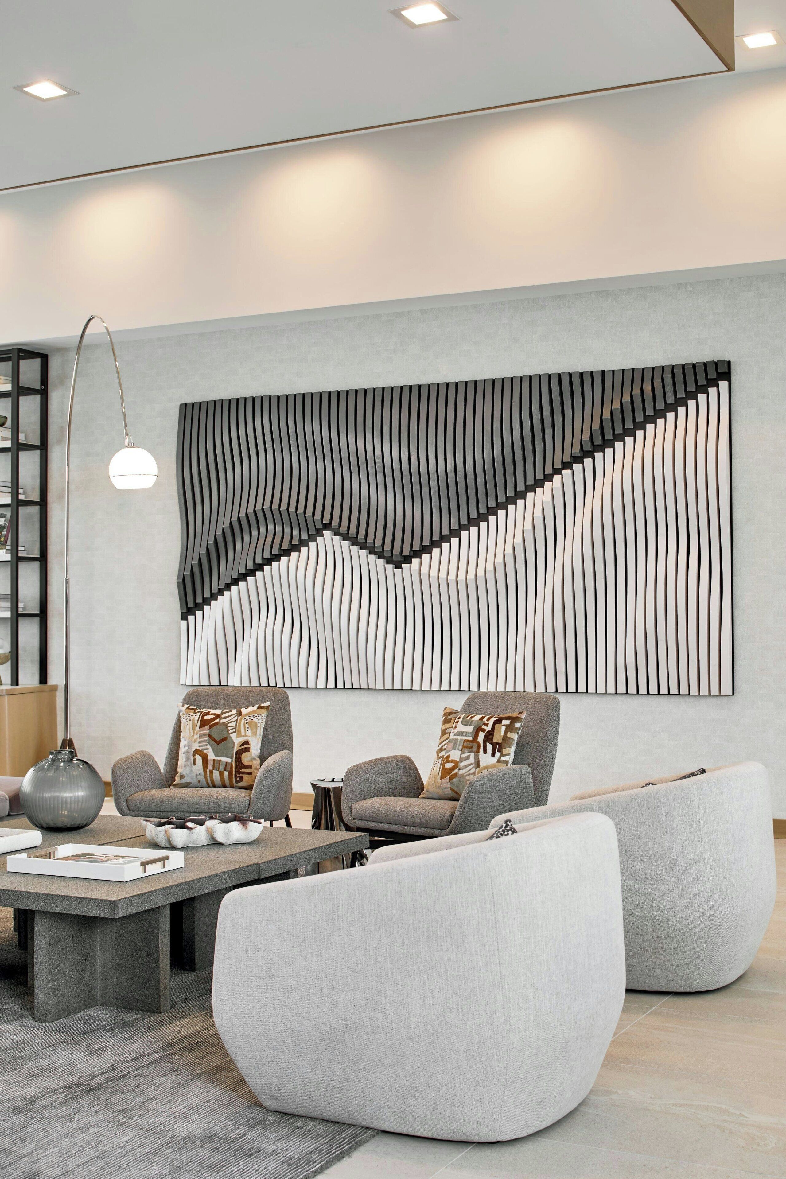 Uma sala de estar moderna com um grande quadro abstrato, sofás cinza e uma mesa de centro.