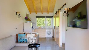 Cozinha moderna com máquina de lavar embutida, área de refeições com mesa e cadeiras, e uma janela ampla que oferece iluminação natural.