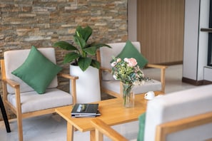 Uma área de estar moderna com duas poltronas, uma mesa, um vaso de flores e um livro.