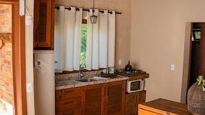 Uma cozinha aconchegante com armários de madeira, bancada e luminária pendente.