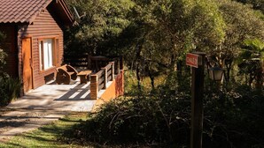 Uma cabana de madeira com varanda, um banco de pedra e uma placa indicando uma promoção.